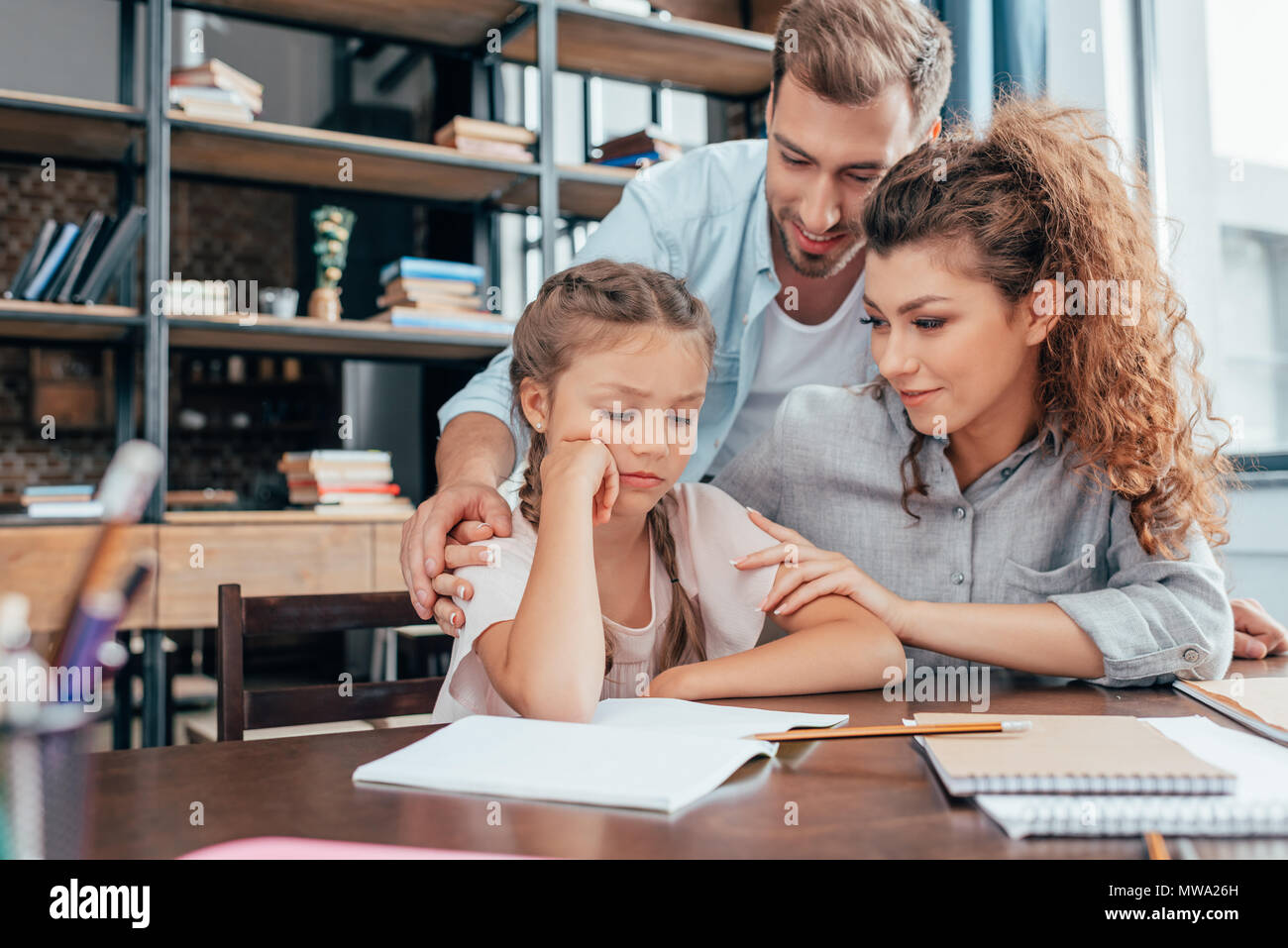 parents doing homework with depressed little daughter Stock Photo - Alamy