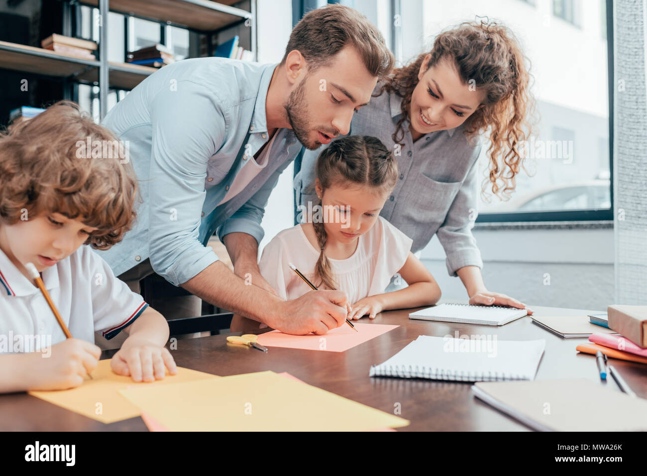 parents doing homework with adorable little kids Stock Photo - Alamy