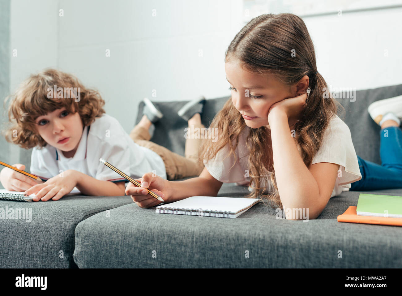 adorable little brother and sister doing homework together on couch ...