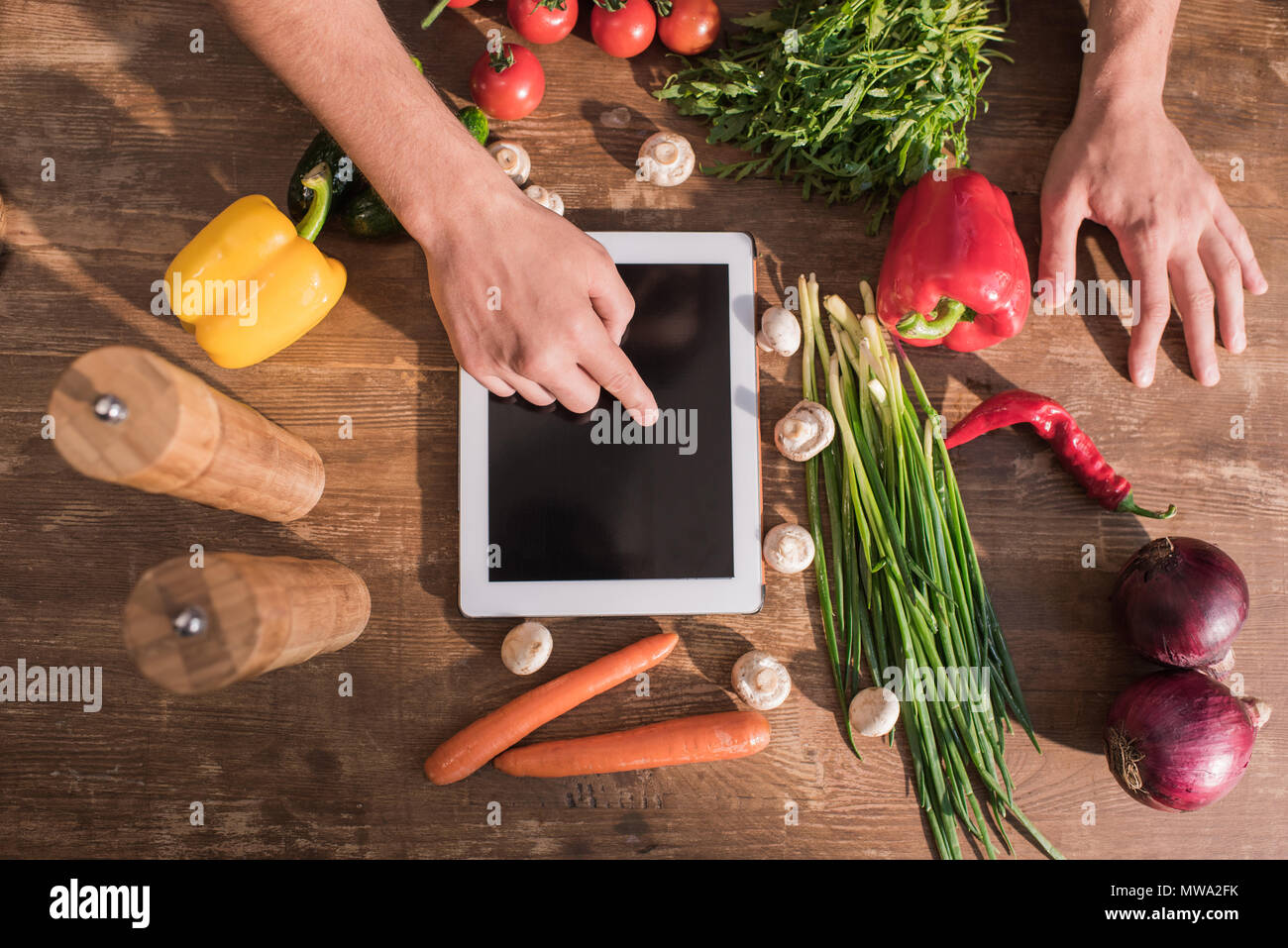top view of young man cooking with tablet and pointing at blank screen ...