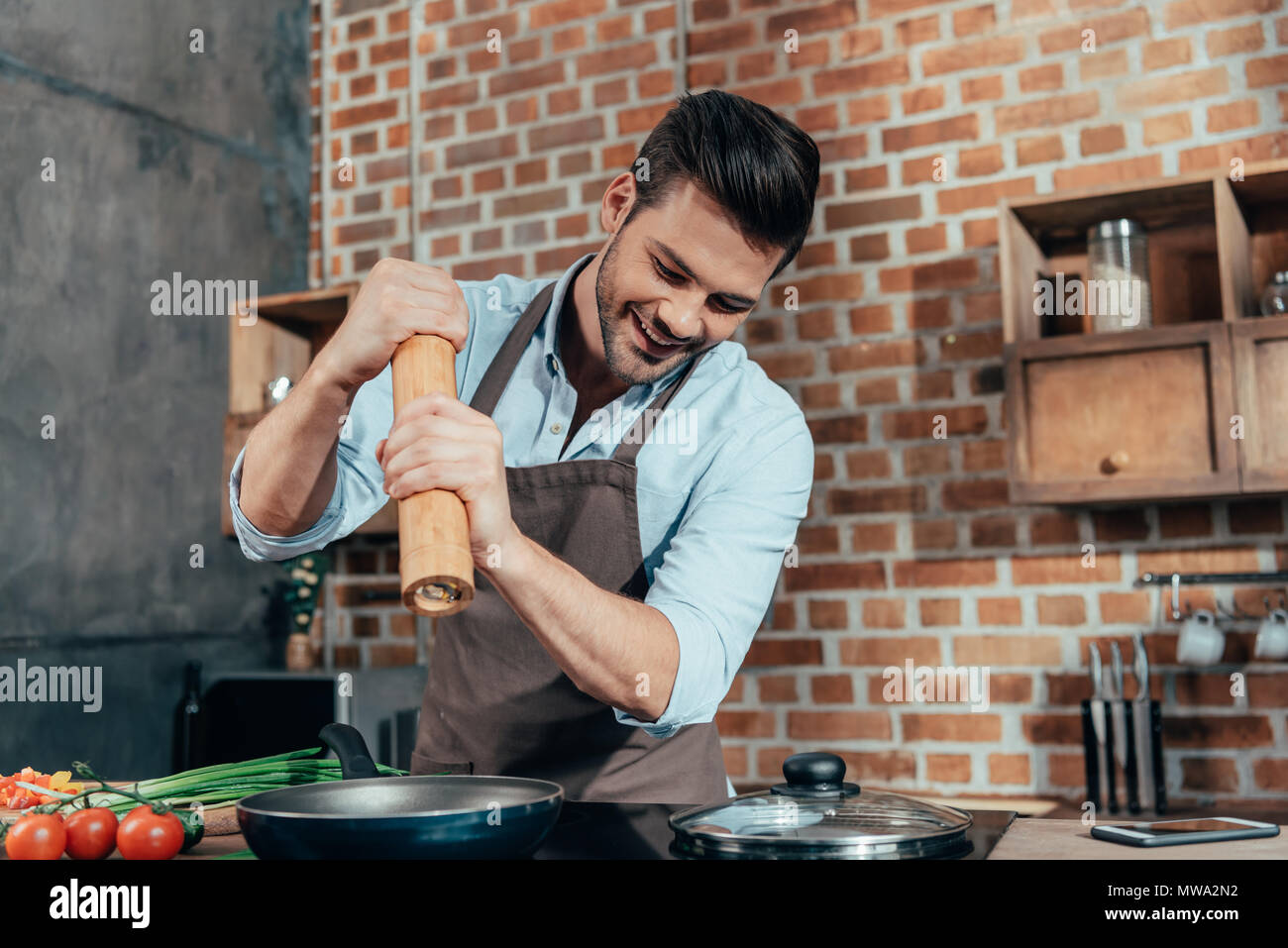 handsome young man adding pepper into frying pan Stock Photo - Alamy
