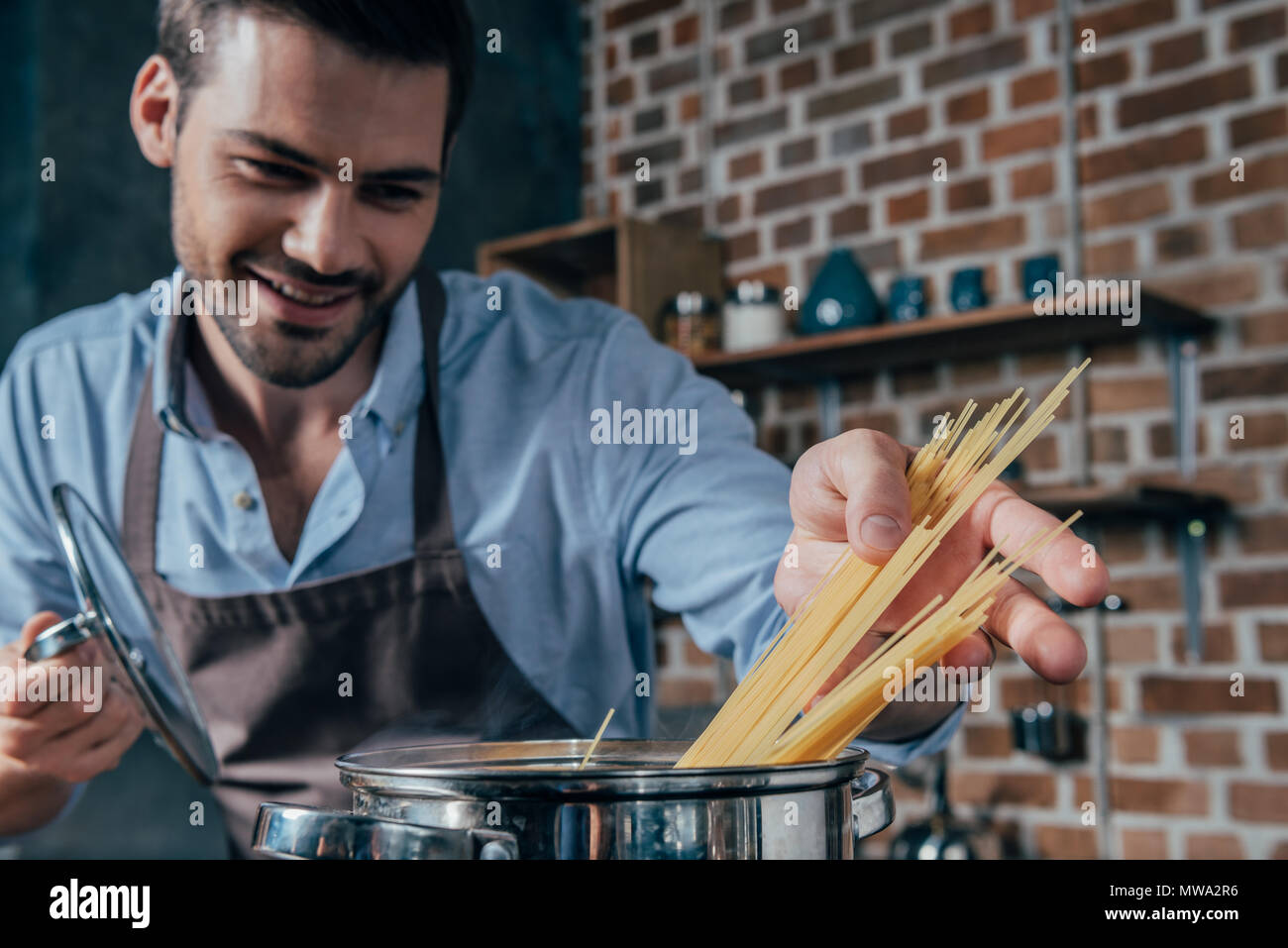 happy young man with apron cooking pasta Stock Photo - Alamy