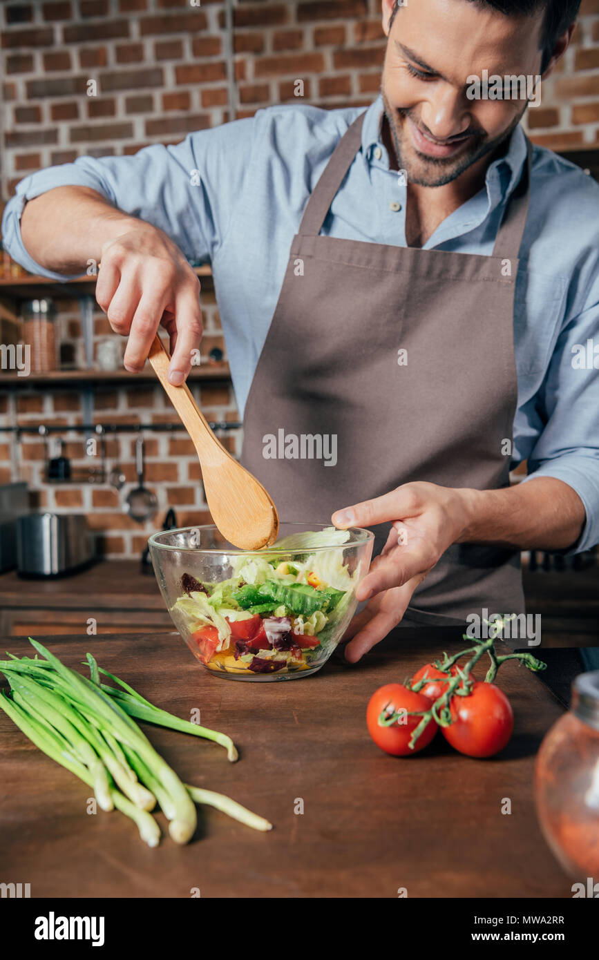happy young man mixing salad Stock Photo - Alamy