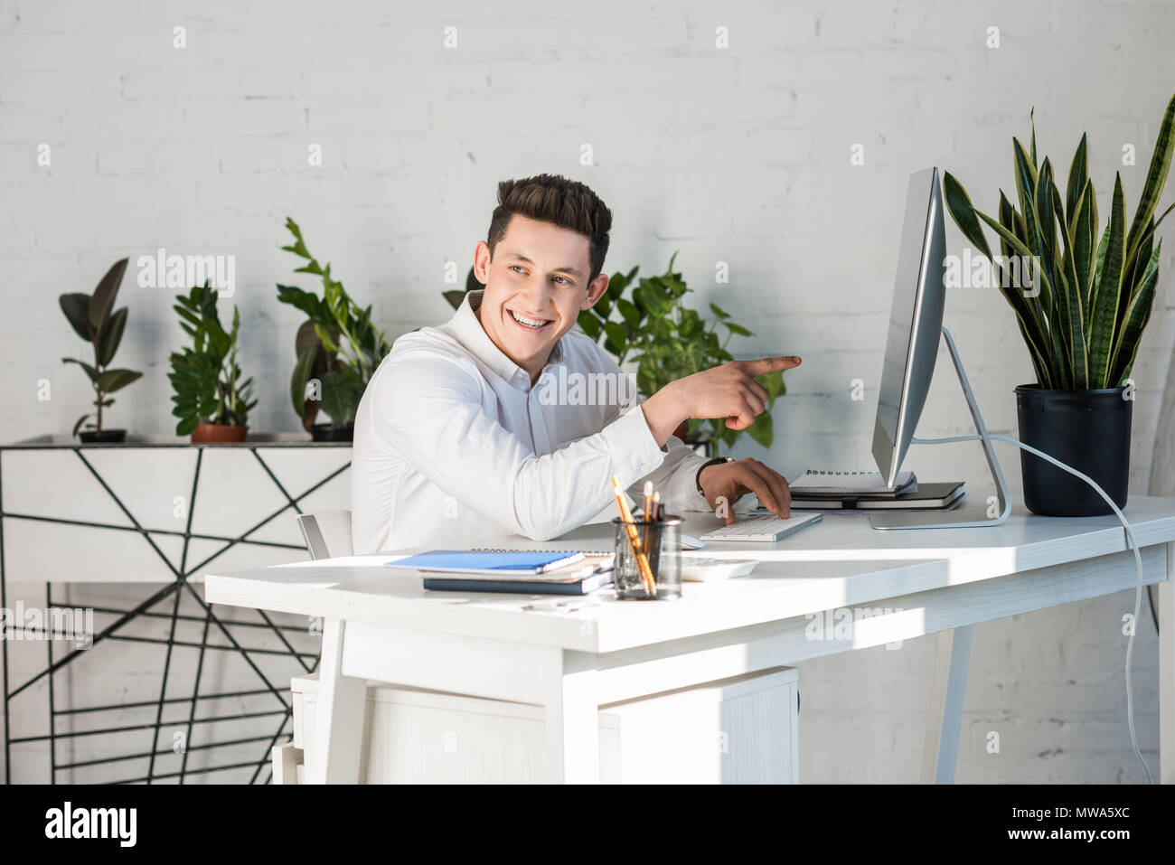 happy young businessman pointing at computer screen Stock Photo - Alamy