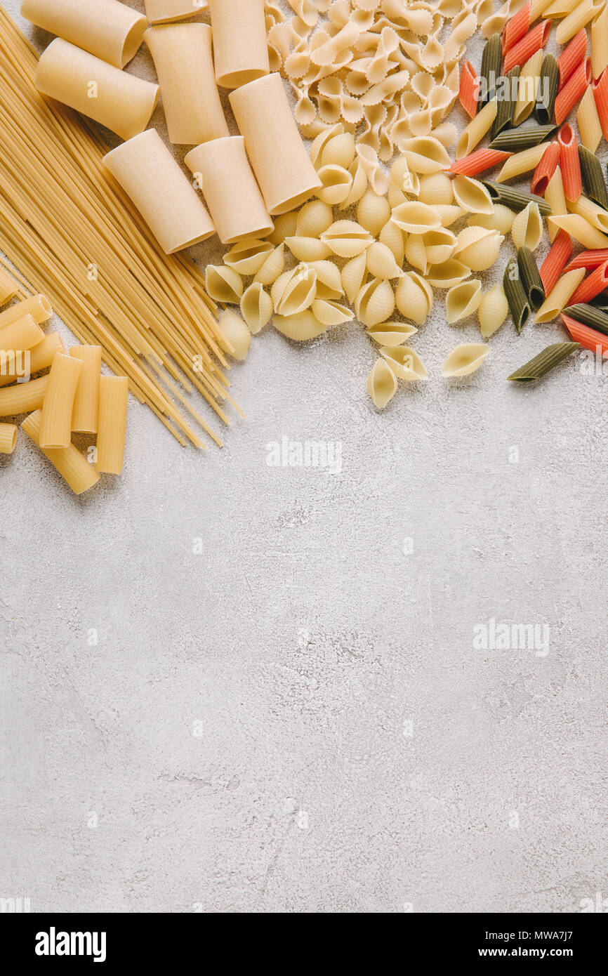 top view of various raw pasta spilled on concrete surface Stock Photo ...