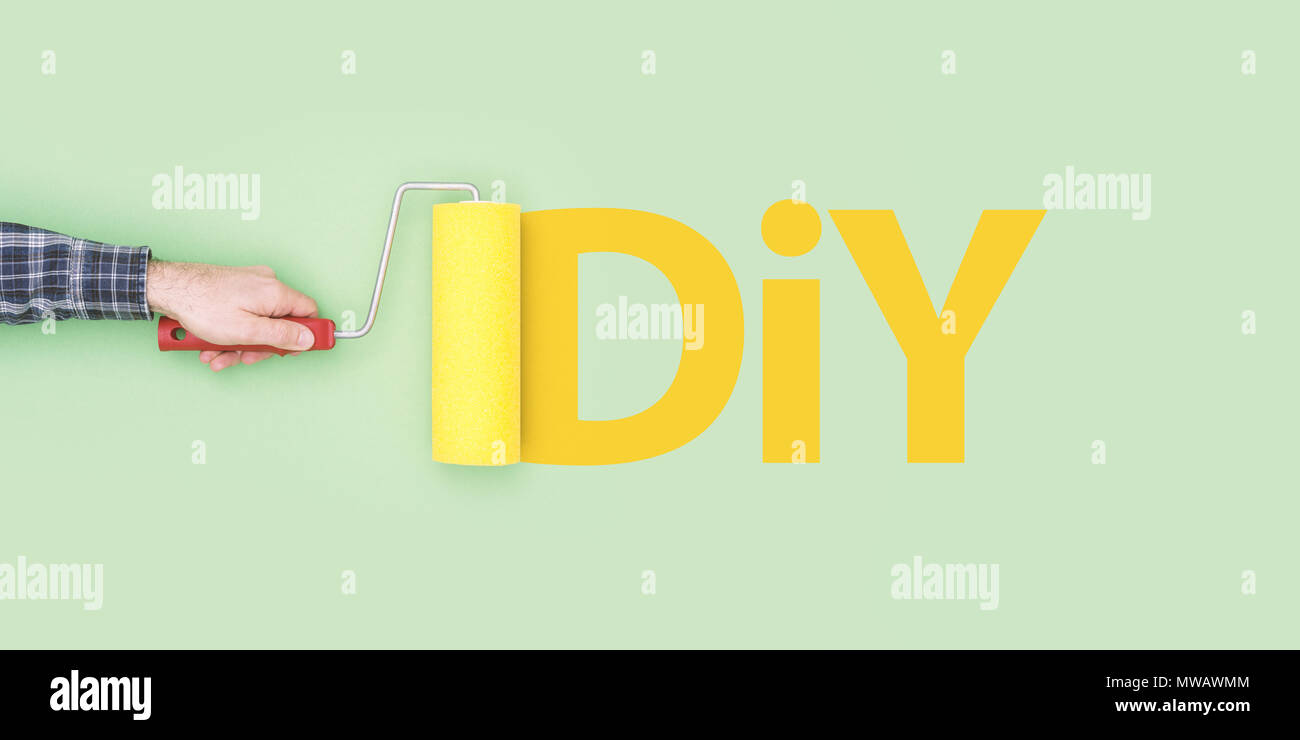 Decorator writing DIY on a wall using a paint roller, creativity and do ...