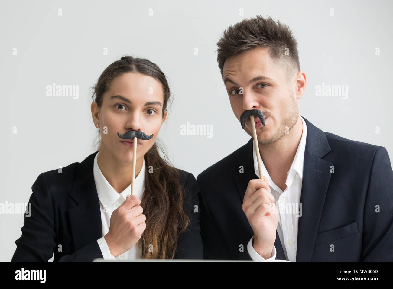 Funny colleagues making silly faces holding fake mustache, heads Stock ...