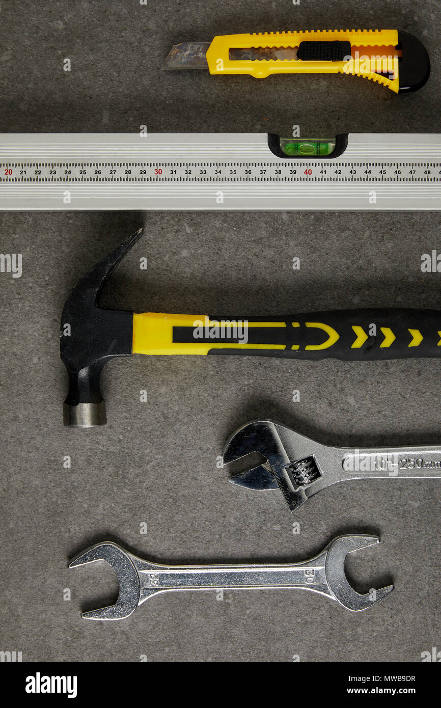 spirit level, hammer, adjustable wrench ans spanner on gray surface ...