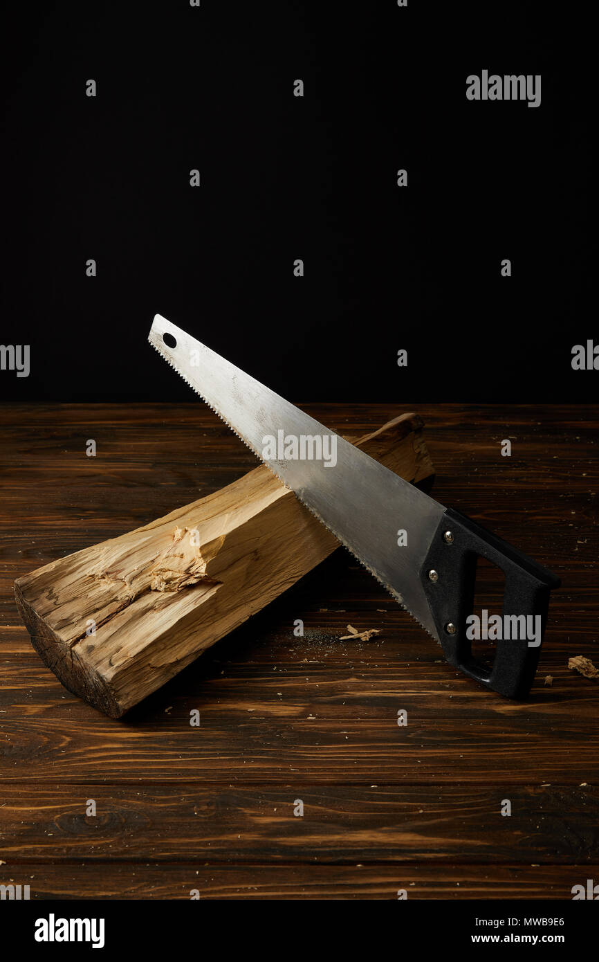 handsaw and log at table on black background Stock Photo - Alamy