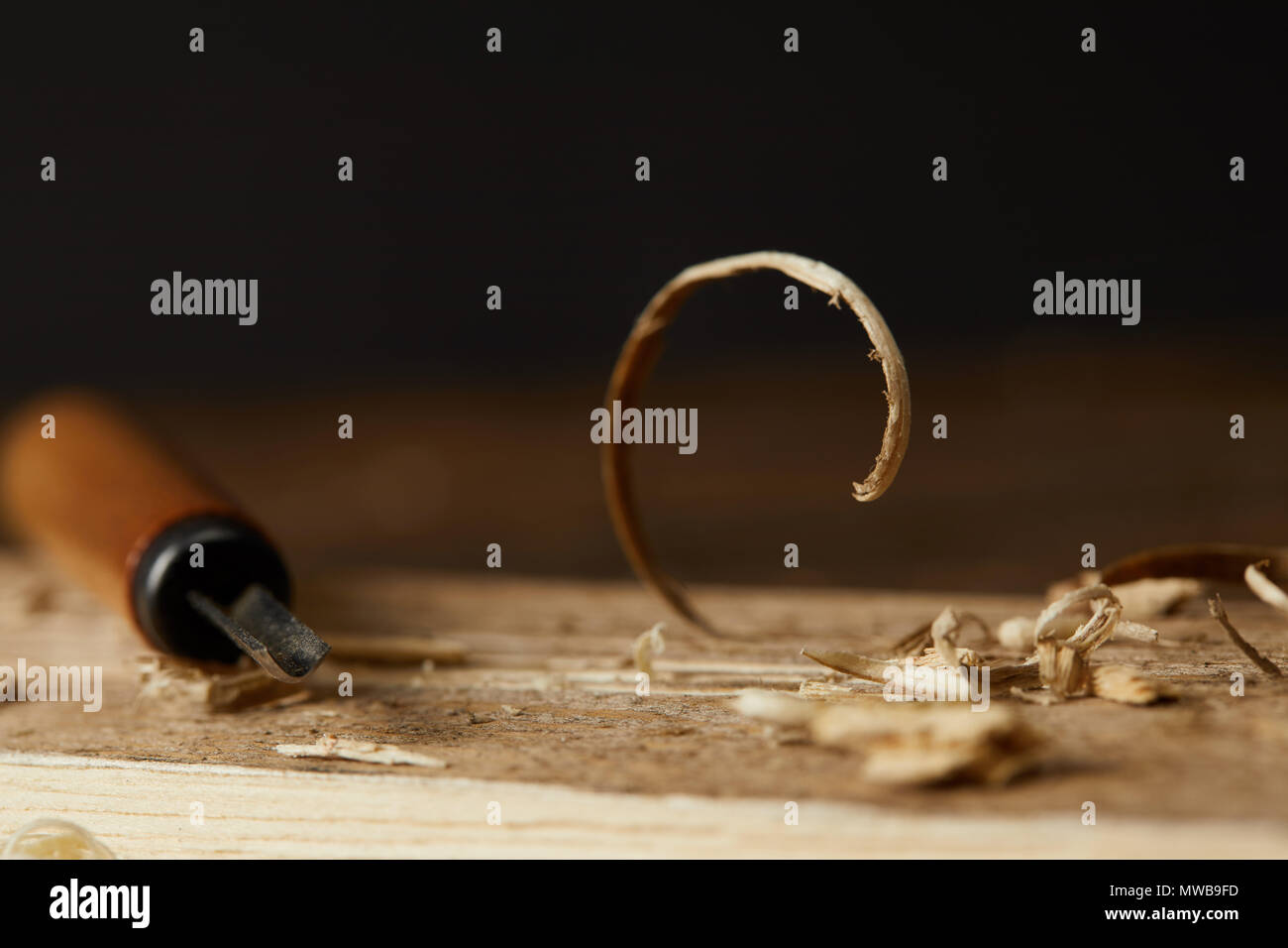 closeup view of chisel and wooden scobs on blurred black background ...