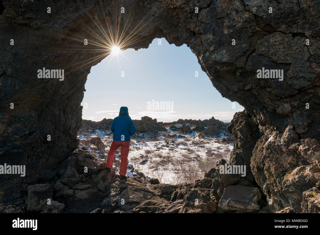 Man in a rock arch, sun shining, volcanic landscape, Krafla volcanic ...