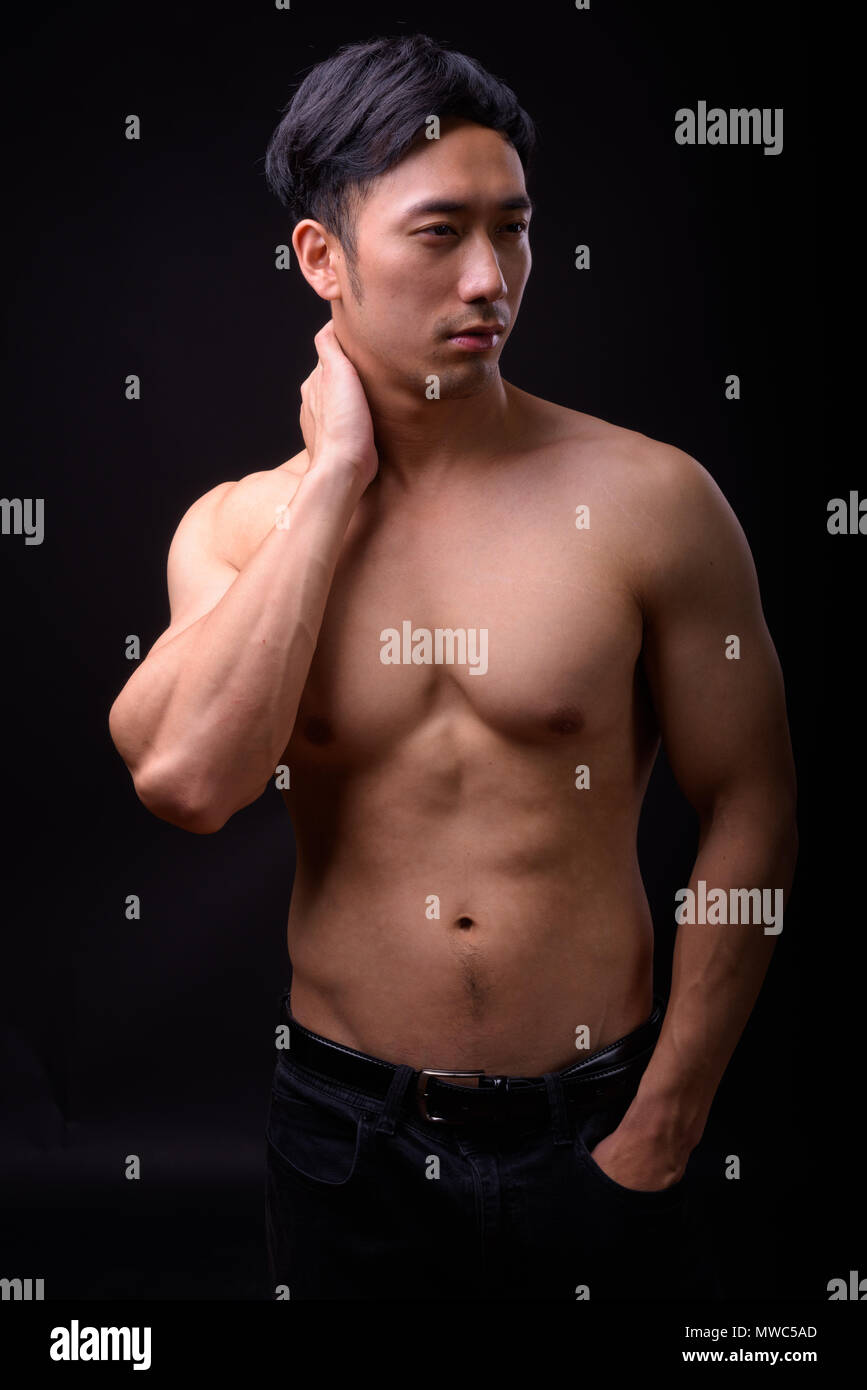 Young handsome Asian man shirtless against black background Stock Photo ...