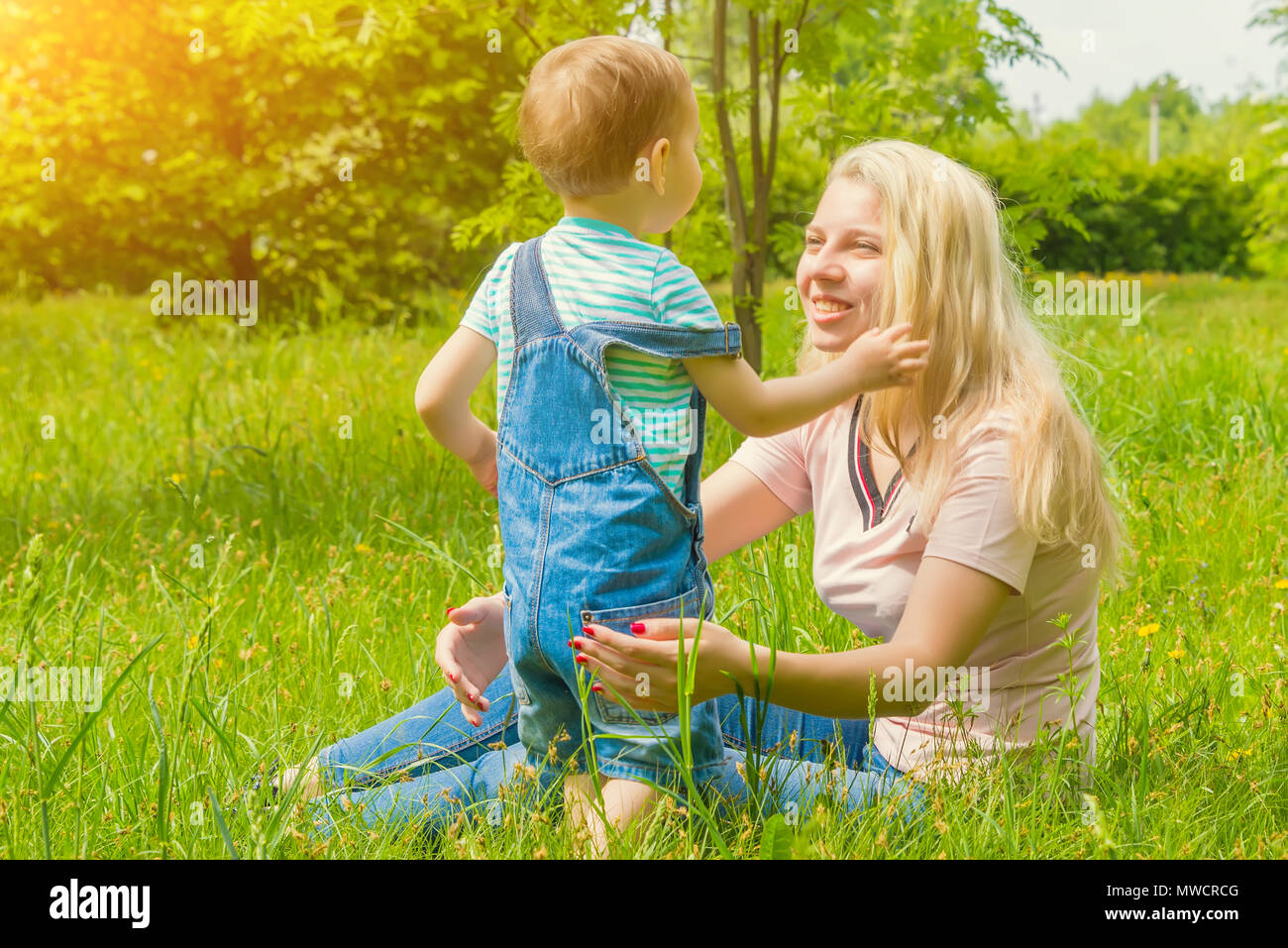 mother and child in nature in the Park, resting on the green grass in ...