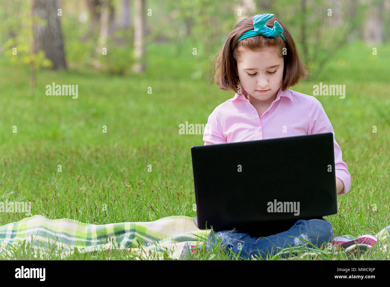 girl child with laptop outdoors resting on green grass Stock Photo - Alamy