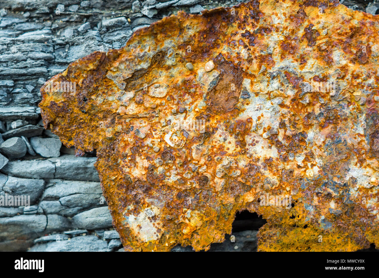 Very rusty metal on a gray cracked rock, bright sunlight, close up ...