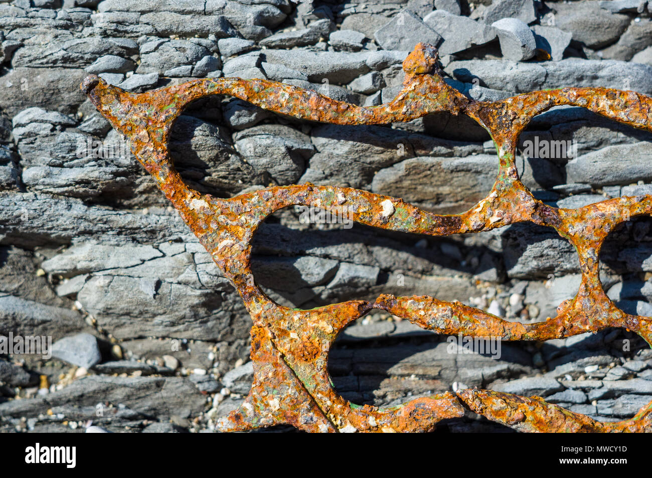 Very rusty metal on a gray cracked rock, bright sunlight, close up ...