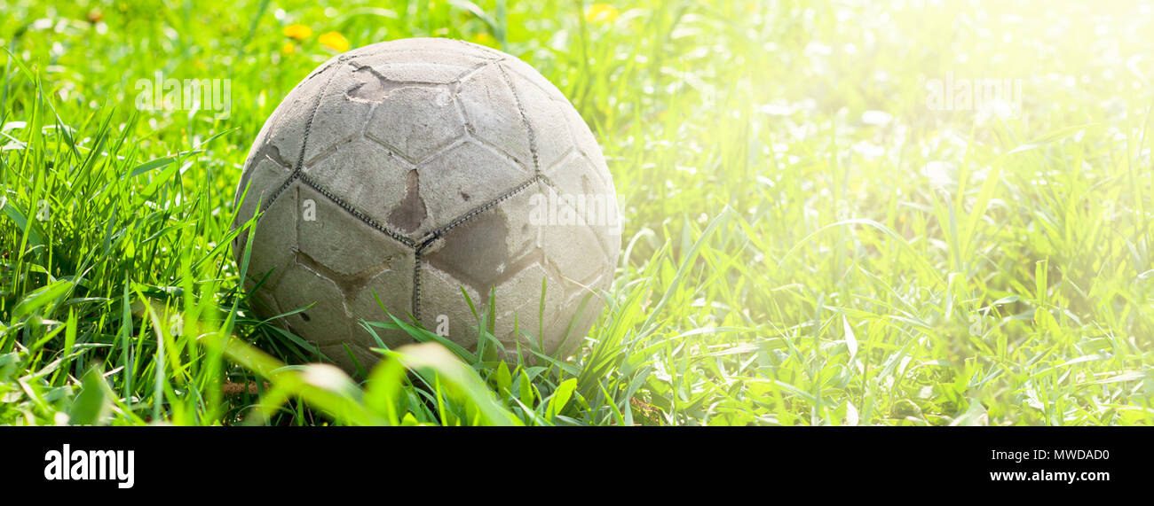 Old soccer ball forgotten in the green grass field. The football ...