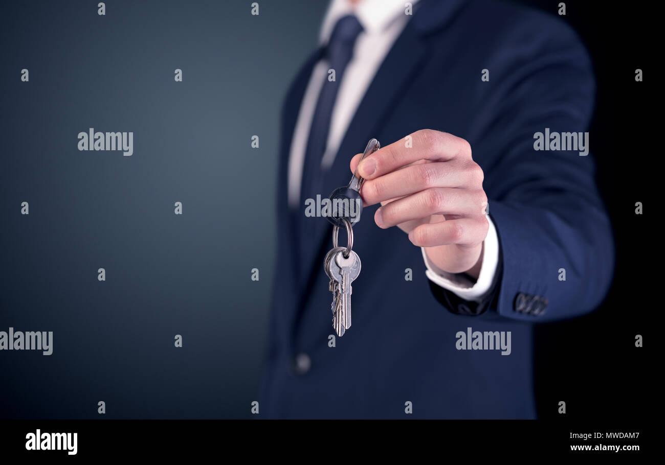 Young businessman hand over keys with empty dark background Stock Photo ...