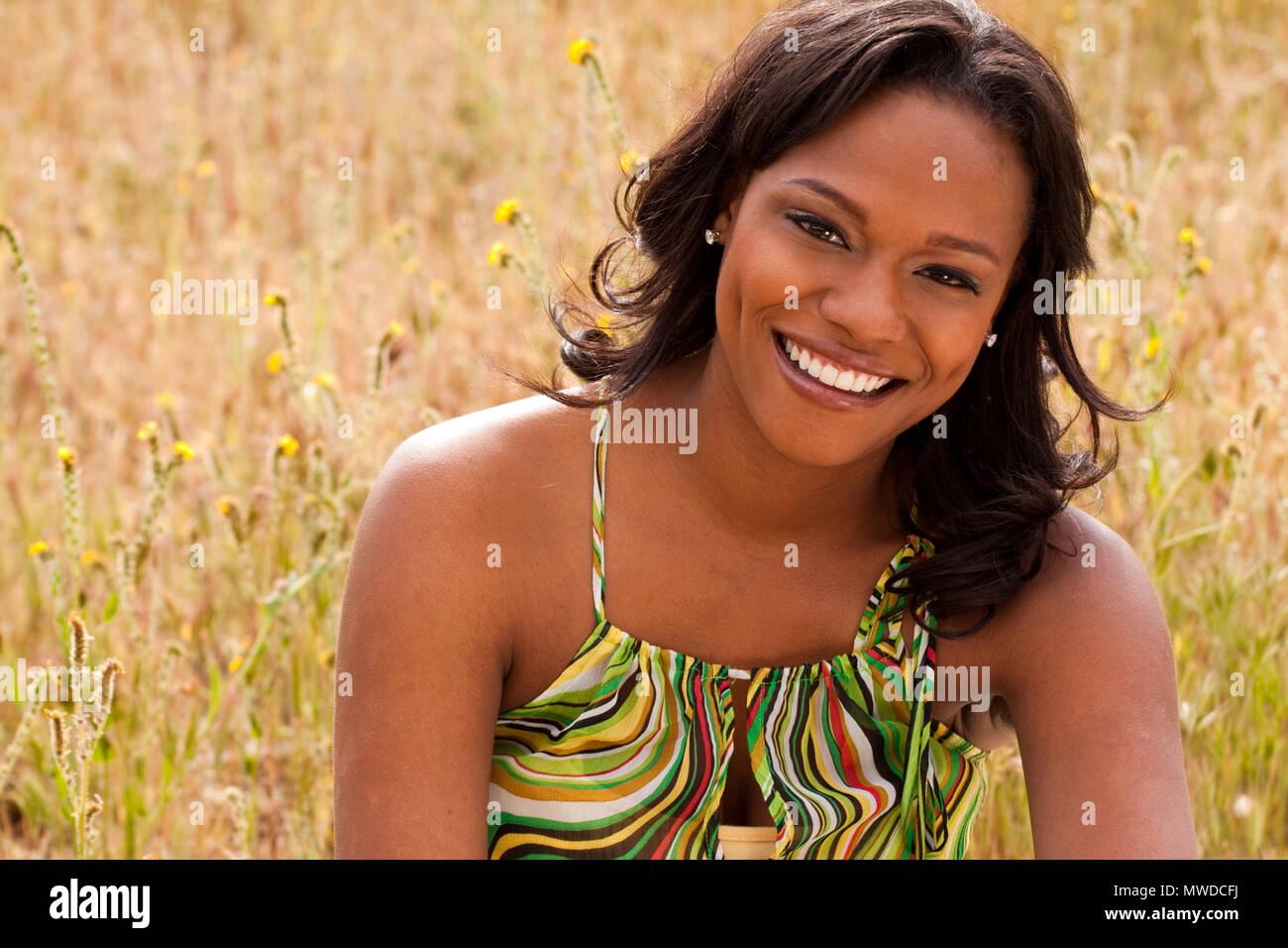 Happy woman sitting in a field smiling Stock Photo - Alamy