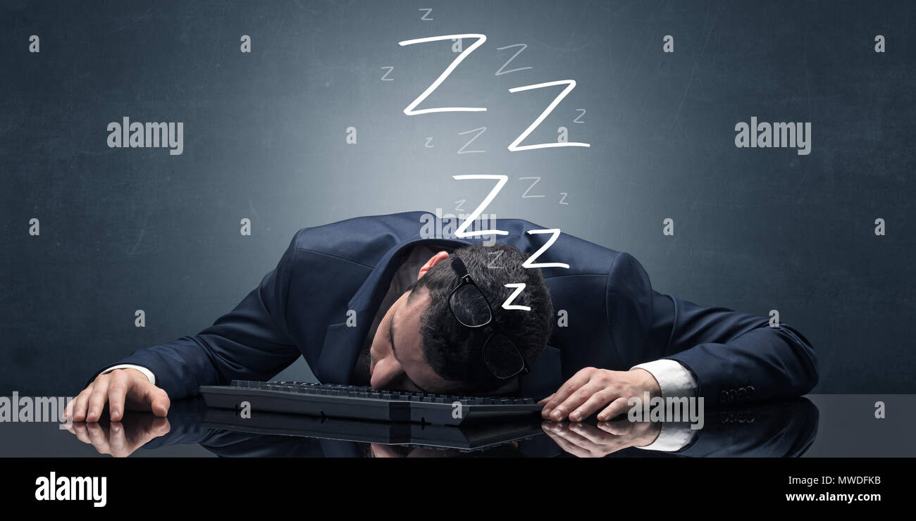 Young businessman fell asleep at the table on his keyboard concept ...