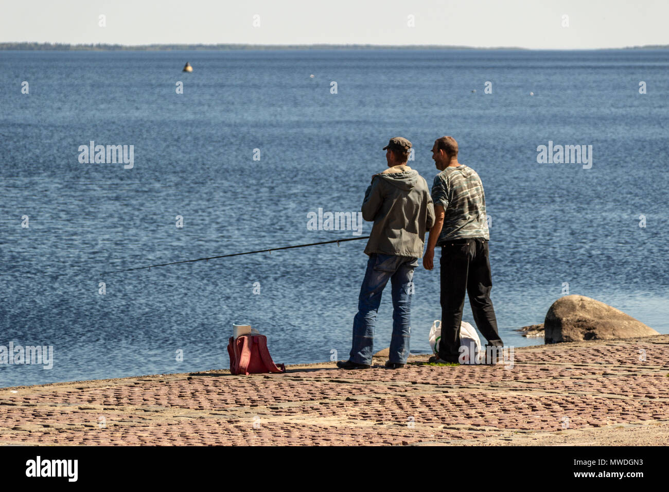 Two men fishing on the waterfront of the city Stock Photo - Alamy