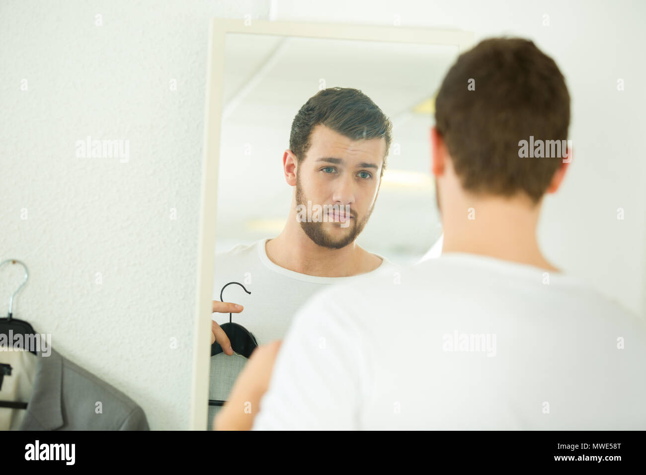 young man trying shirt on in front of mirror Stock Photo - Alamy