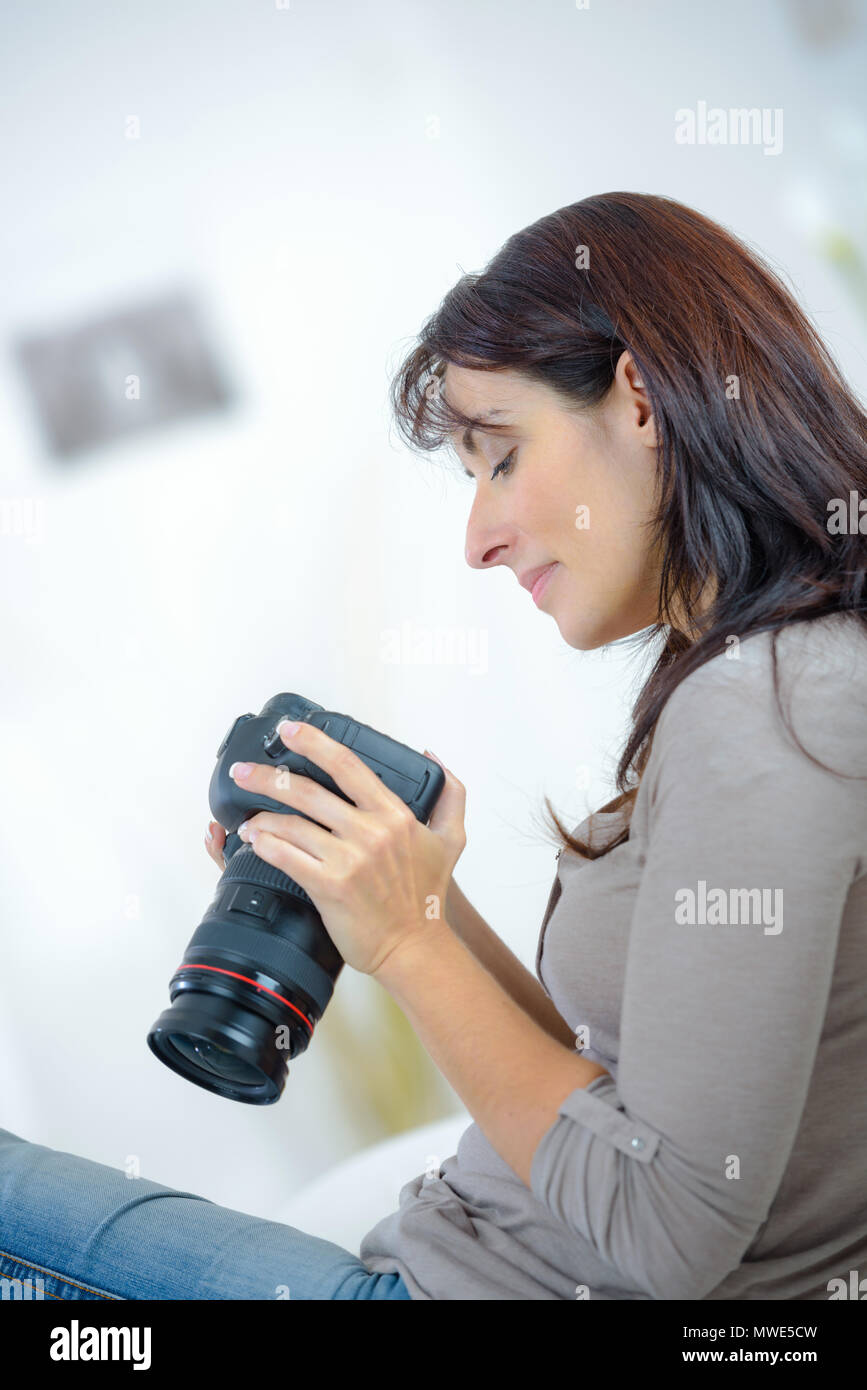 female photographer sitting at home checking camera Stock Photo - Alamy