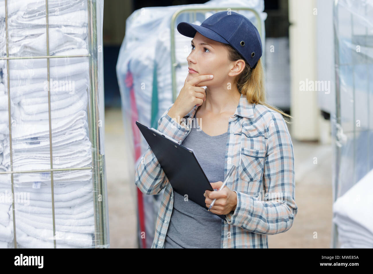 female worker writing inventory and thinking in warehouse Stock Photo ...