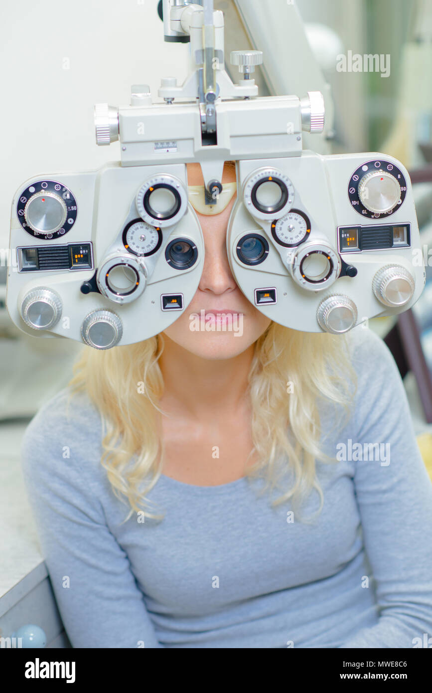 Woman behind optician's eye testing equipment Stock Photo - Alamy