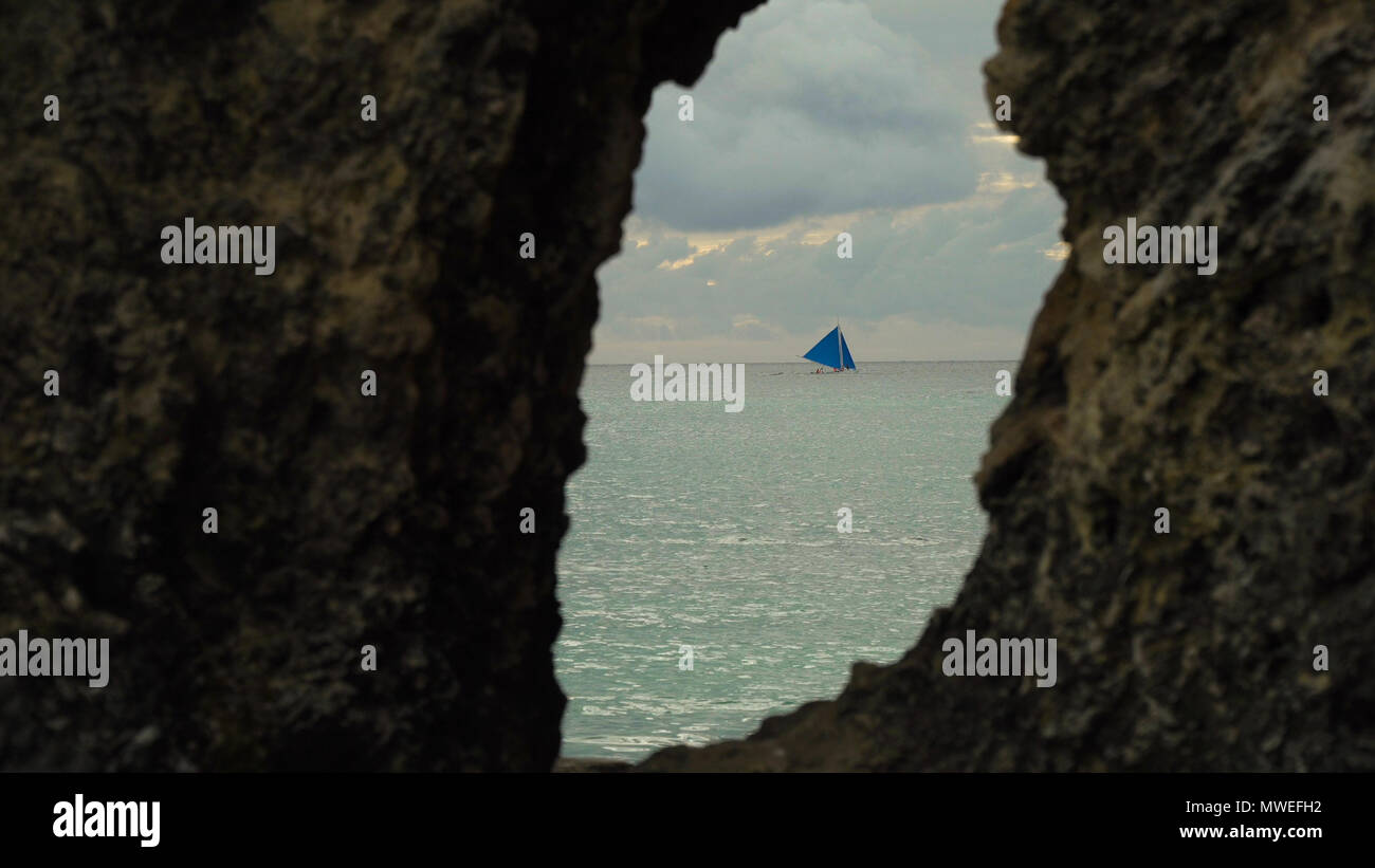 Sailing boat view through a hole in the rock. Sailing ship yachts with ...