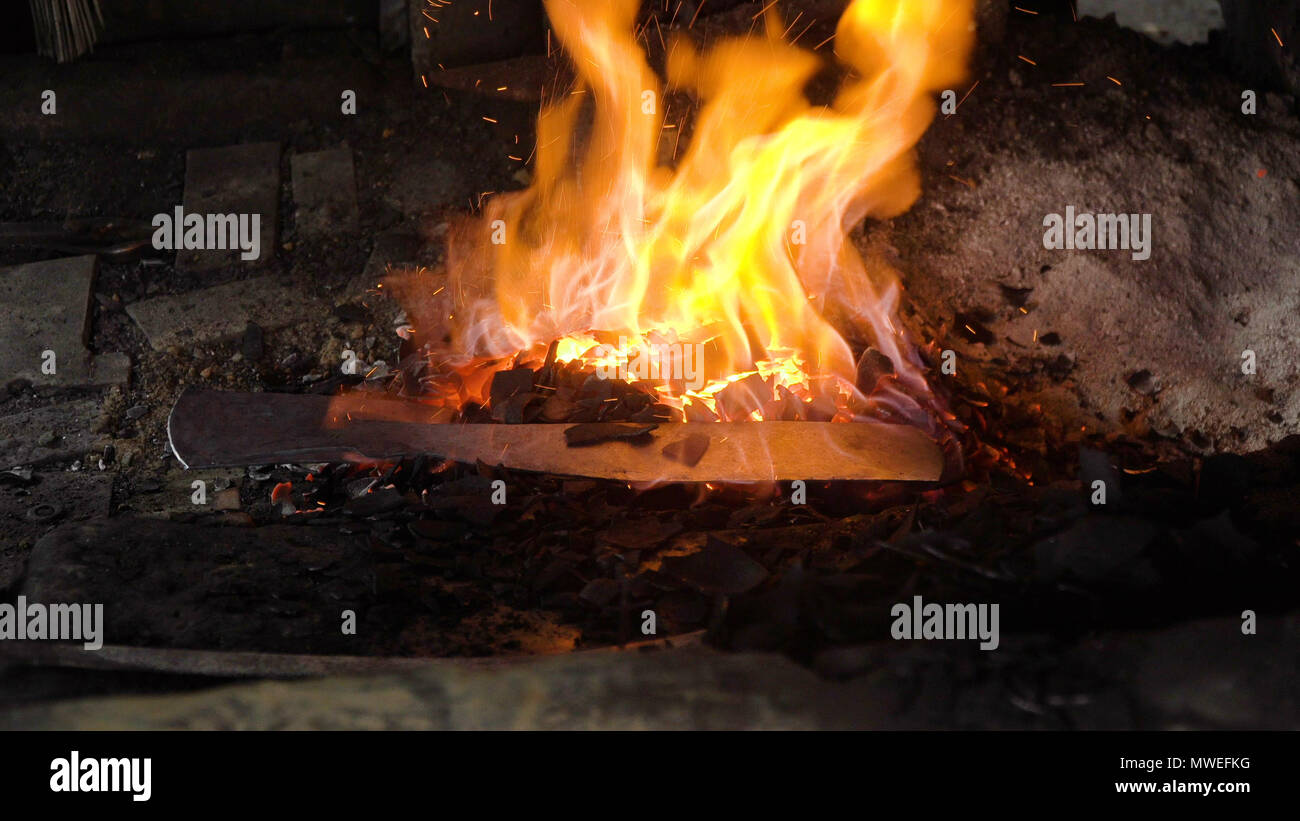 Blacksmith furnace with a hot iron, burning embers, sparks. Blazing ...