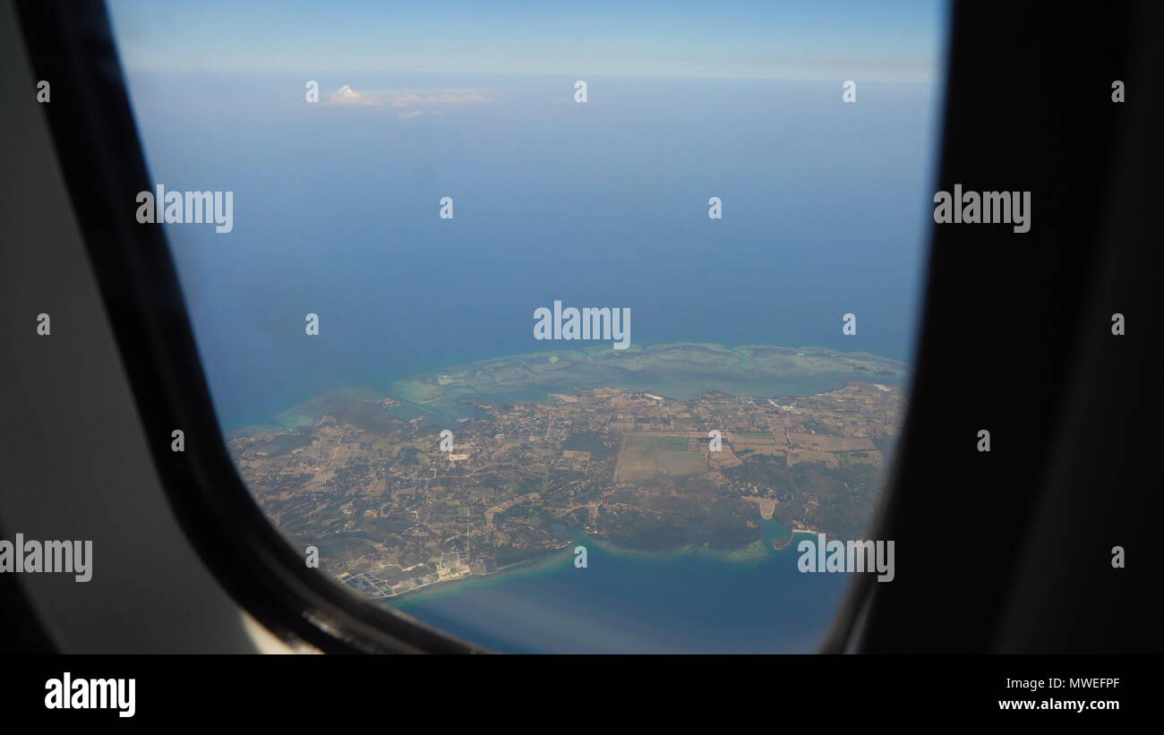 View through an airplane window on the tropical island, ocean, sky and ...