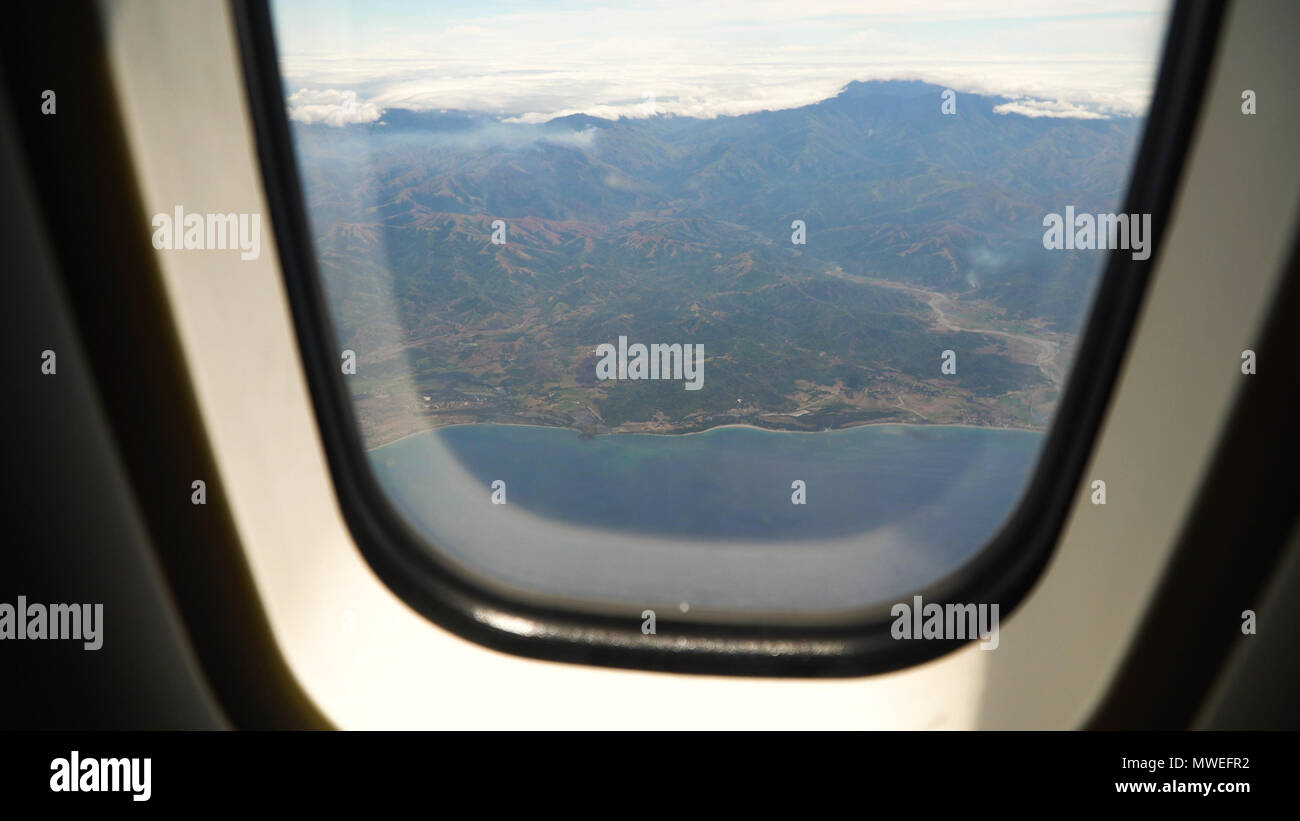 View through an airplane window on the tropical island, ocean, sky and ...