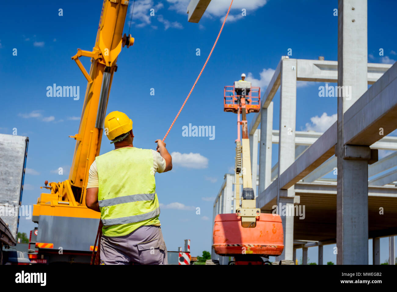 Worker is helping mobile crane with rope to manage concrete joist for ...