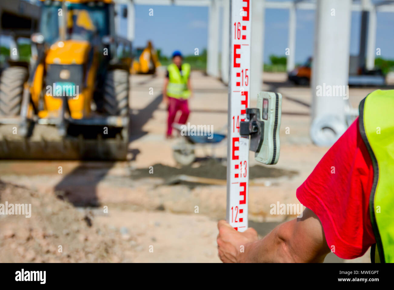 Construction worker is holding leveling rod to help surveyor, geodesist ...