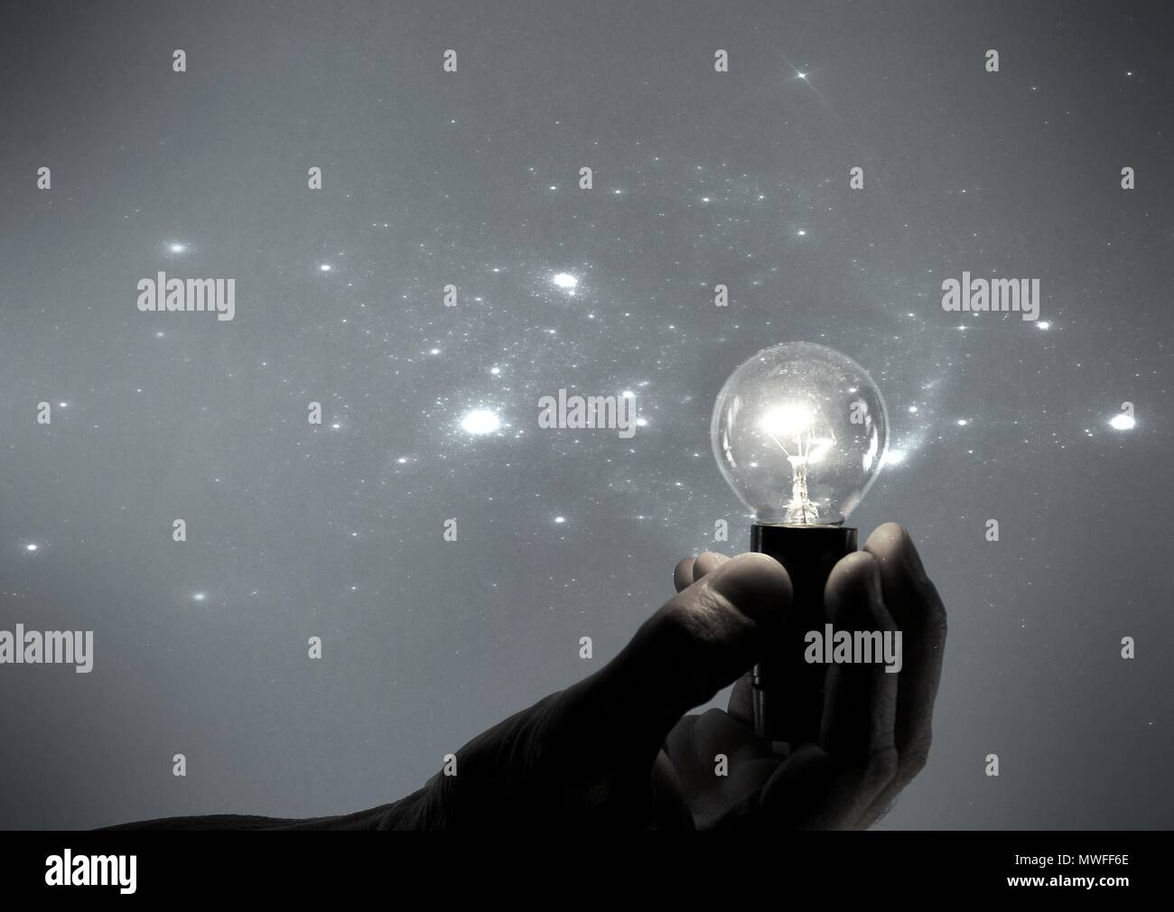 Male hand with incandescent light bulb and stars light effect on gray ...
