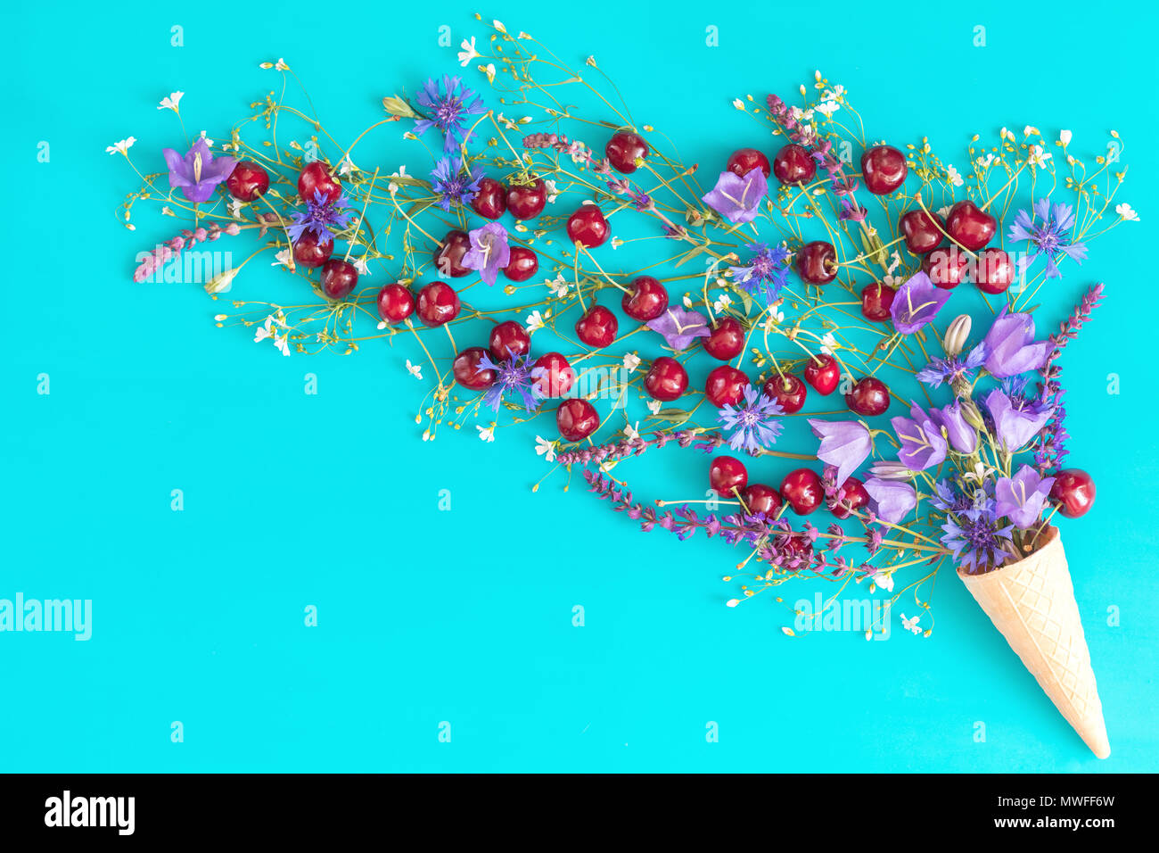Waffle cone with red cherries, cornflower, blue bells and white flowers ...