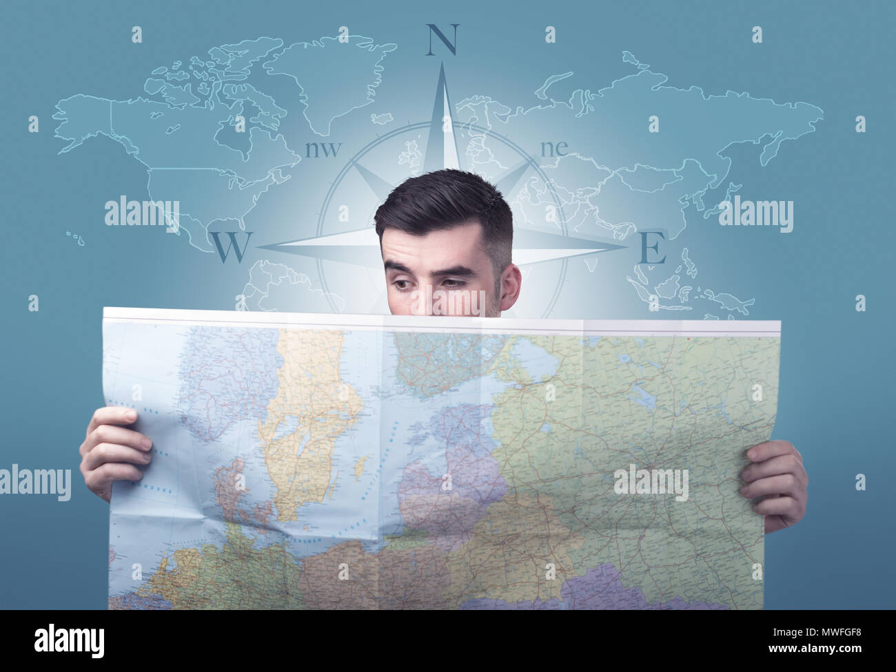Handsome young man holding a map with a world map and a compass behind ...