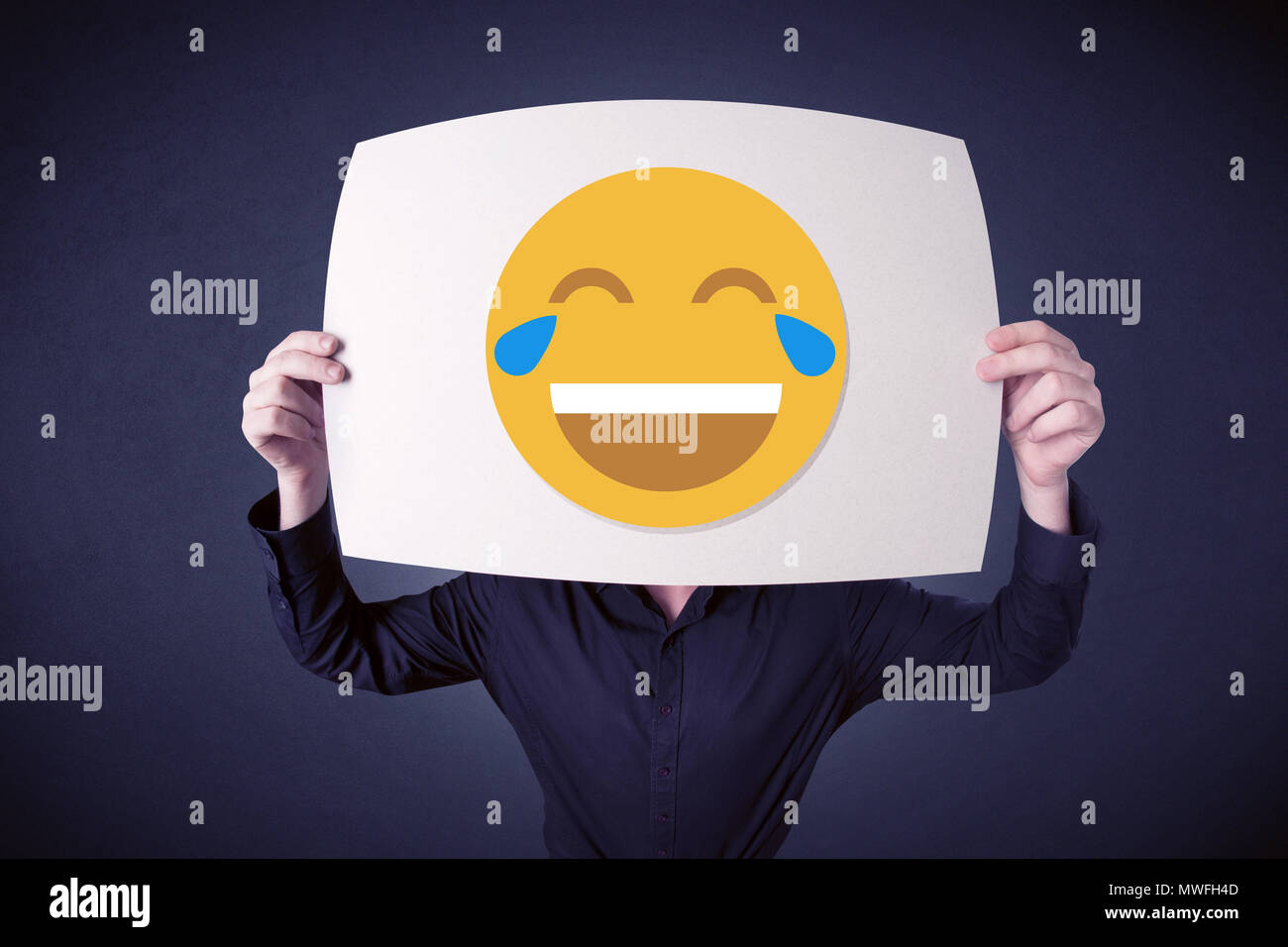 Young businessman hiding behind a laughing emoticon on cardboard Stock ...