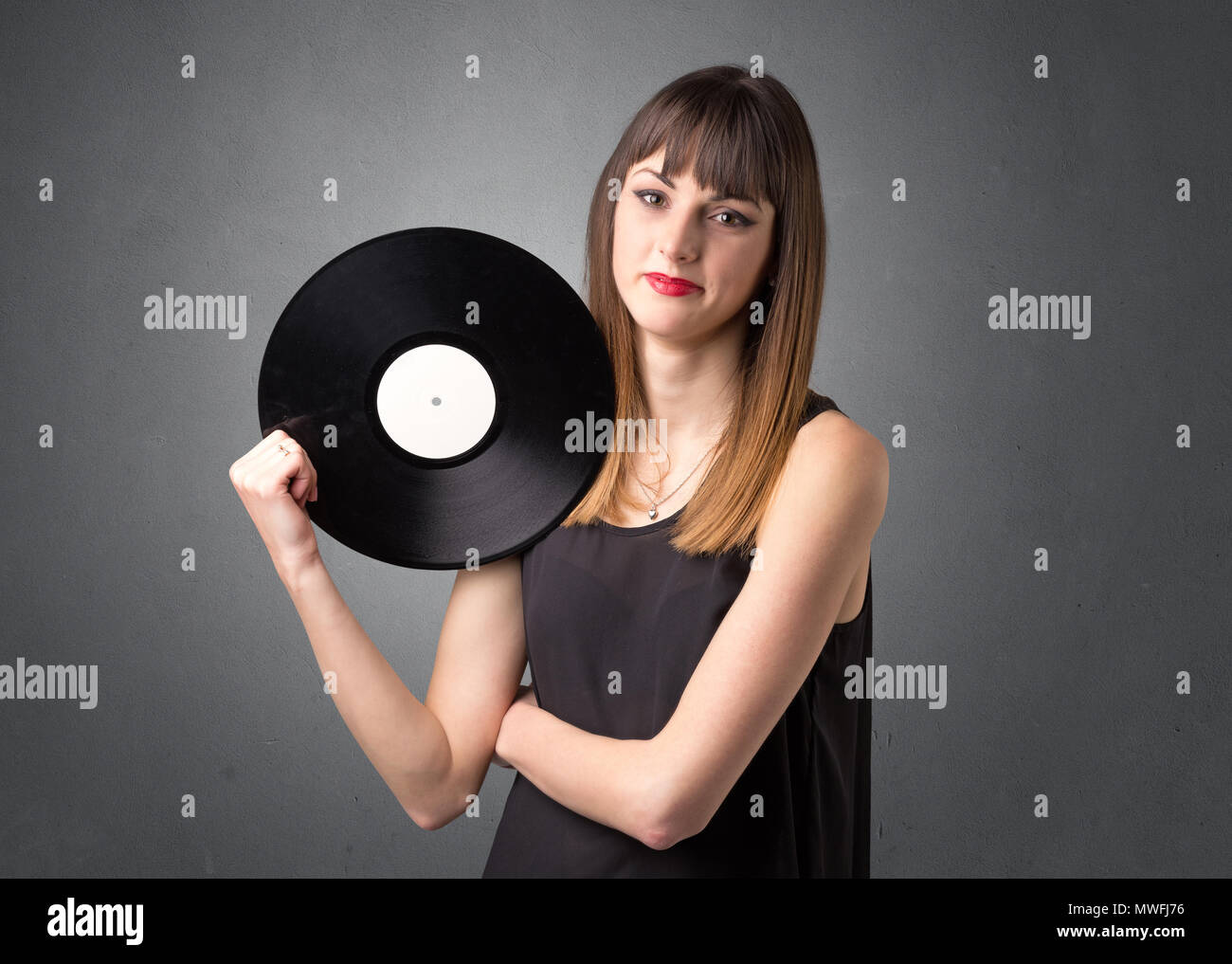 Young lady holding vinyl record on a grey background Stock Photo - Alamy