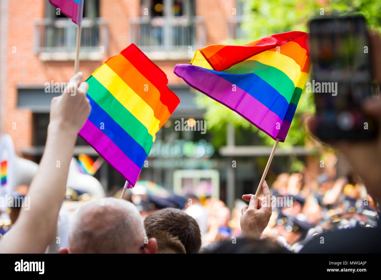 Rainbow flags flying in bright sun on the sidelines of a colorful ...