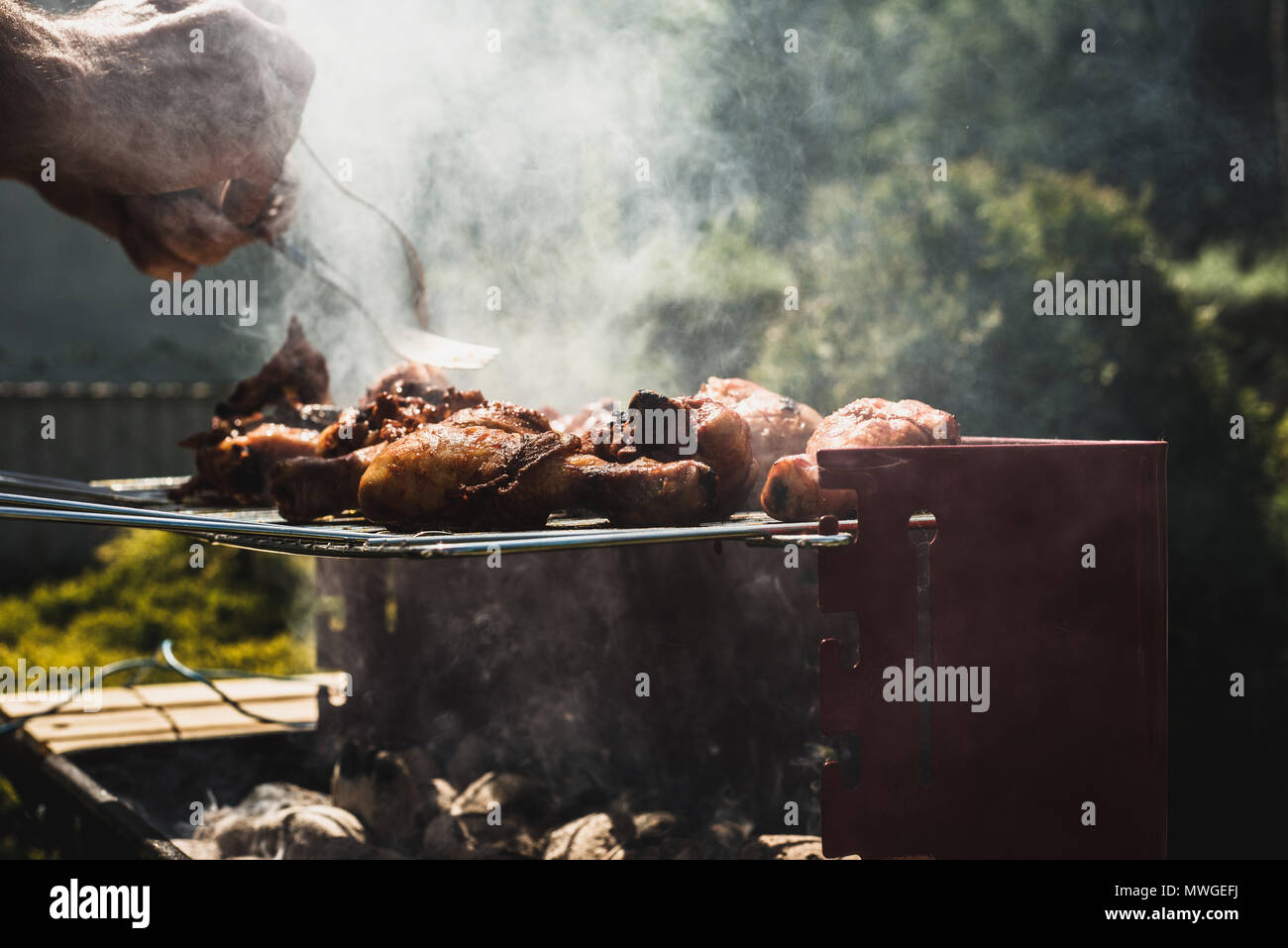 Pulling the chicken on the grill. The man pulls the finished chicken ...