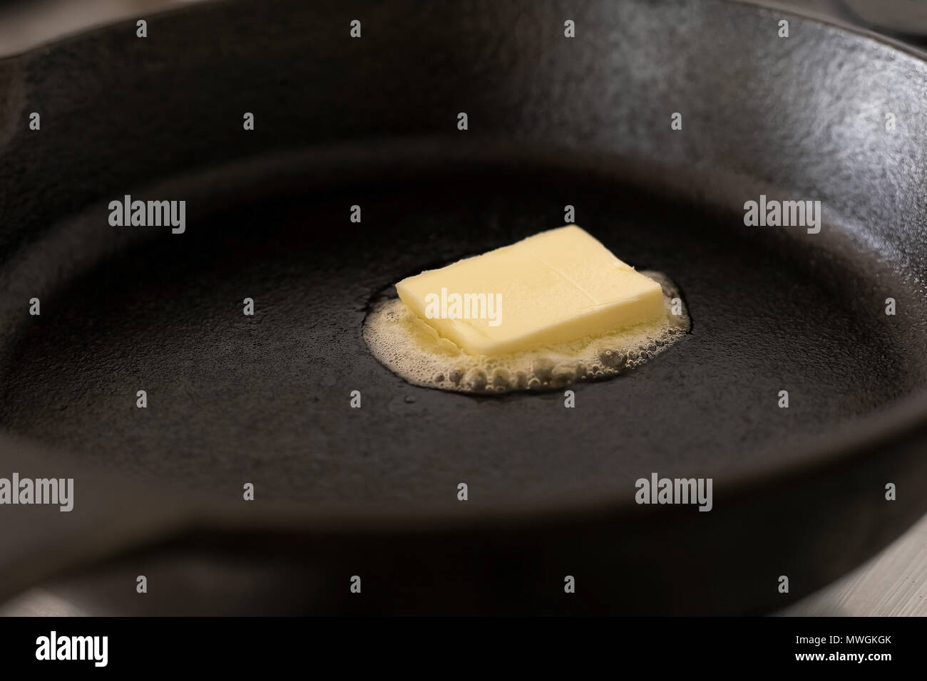 A butter pat melting on a black cast iron frying pan Stock Photo - Alamy