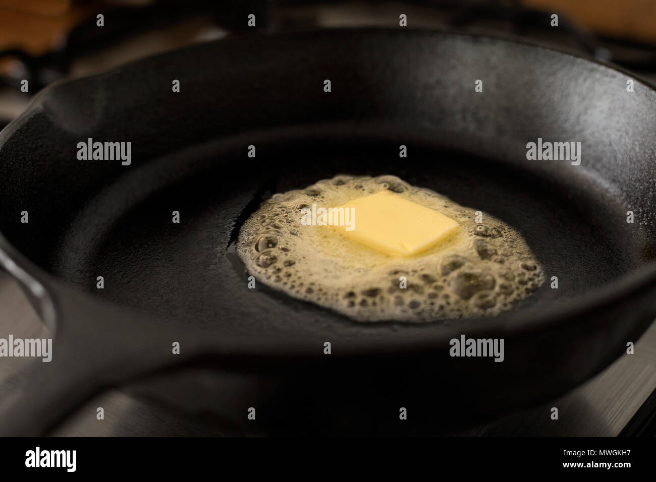A butter pat melting on a black cast iron frying pan Stock Photo - Alamy