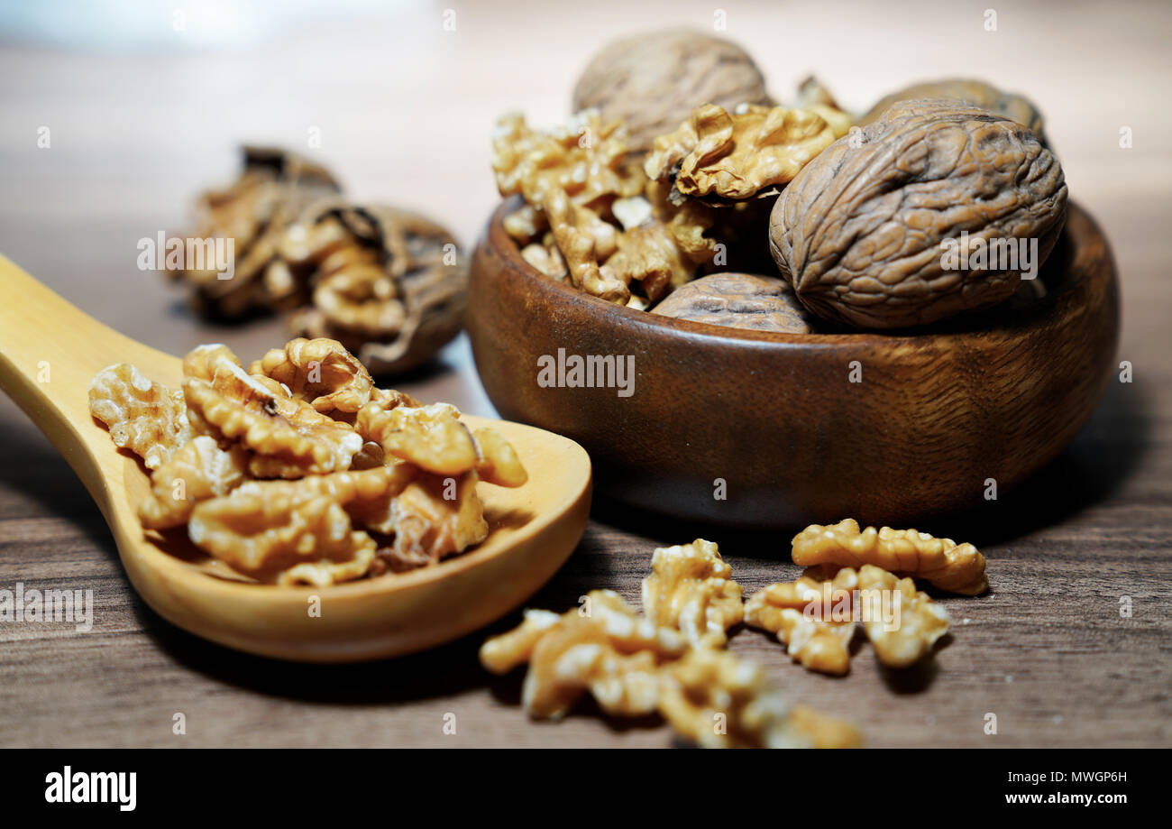 Whole walnuts and kernel walnuts in wooden bowl and wooden spoon on ...