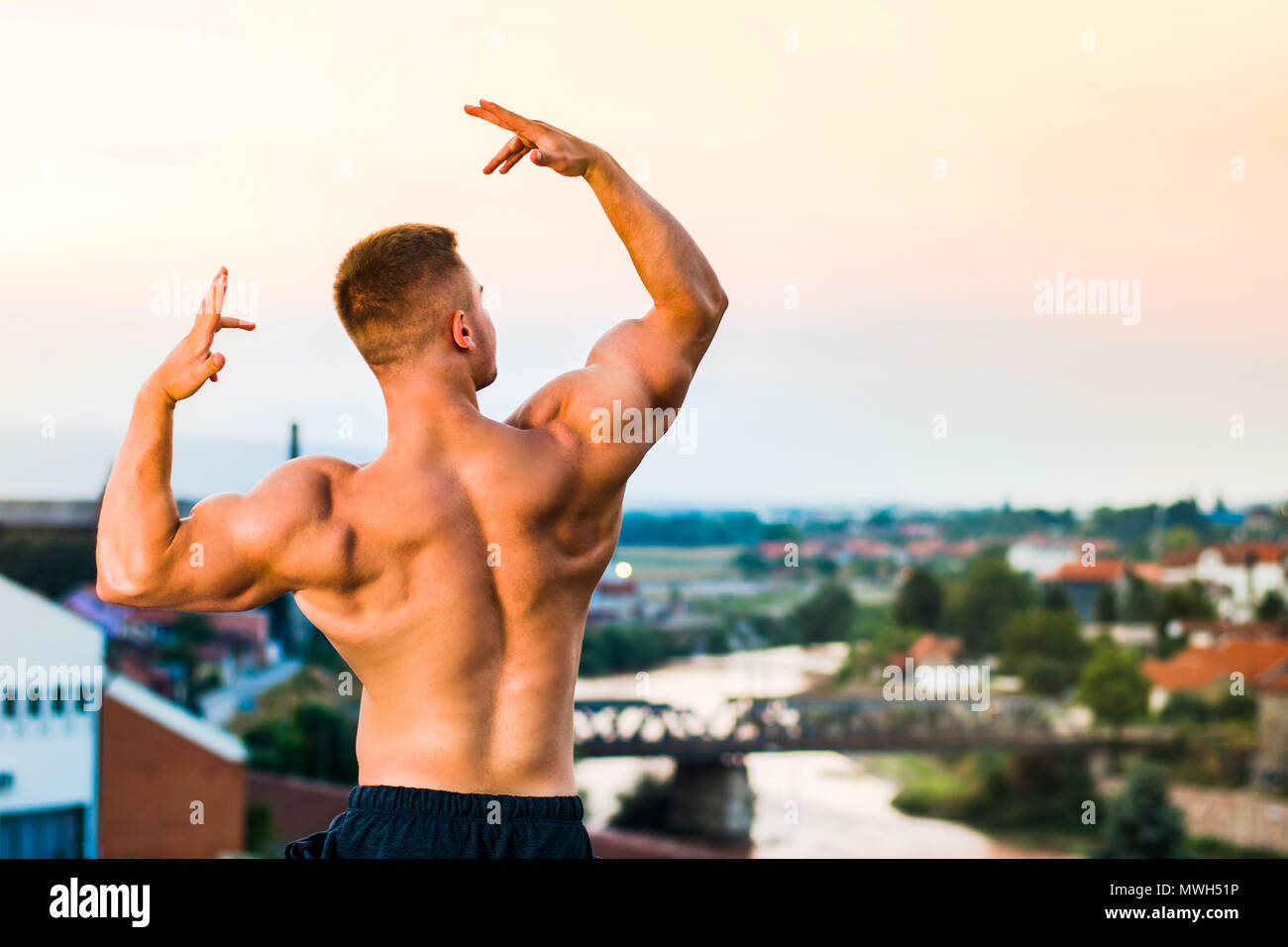 Young bodybuilder flexing muscles on a rooftop Stock Photo - Alamy