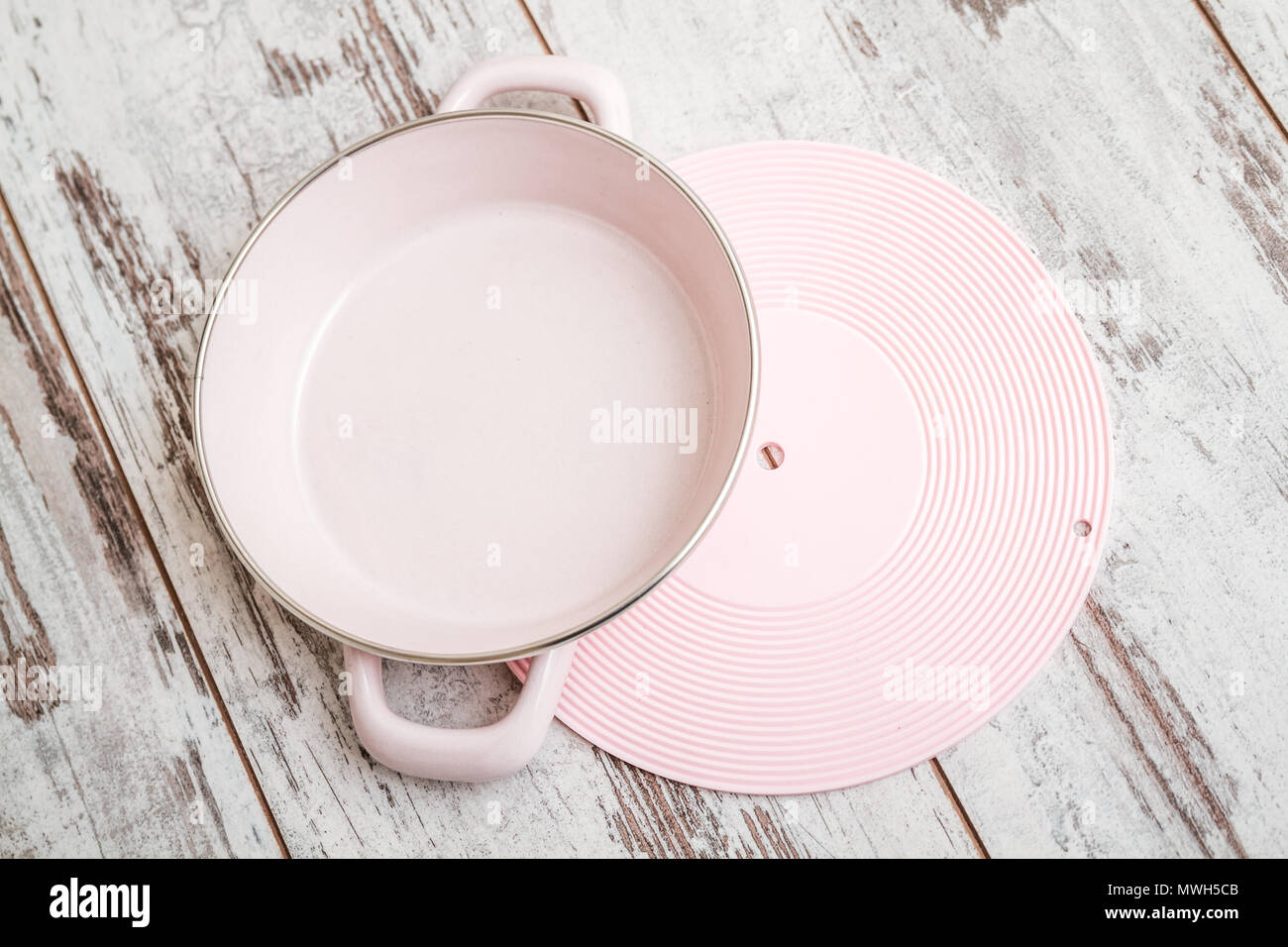 Colorful pink enamel frying pan with handles on white wooden background ...