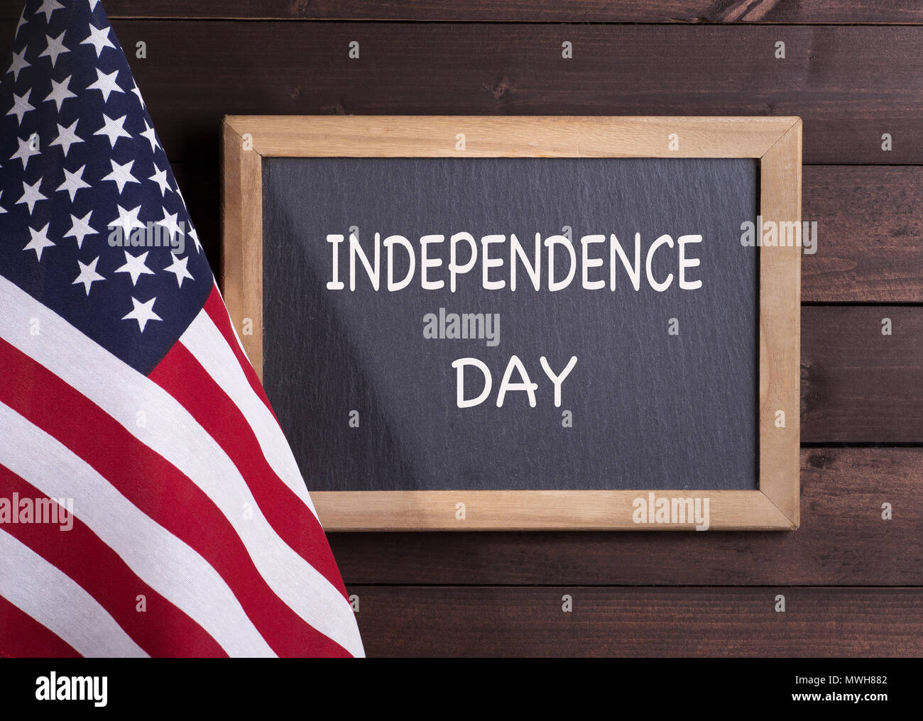 American flag with INDEPENDENCE DAY written on a chalkboard on a rustic ...