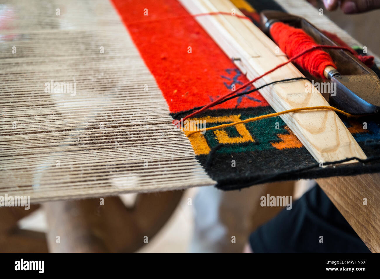 Craftsman making a woven rug from wool dyed by natural colours on hand ...