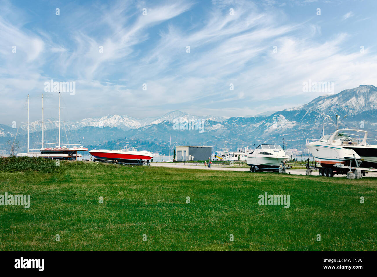 Beautiful view of green lawn in front of embankment with boats on land ...